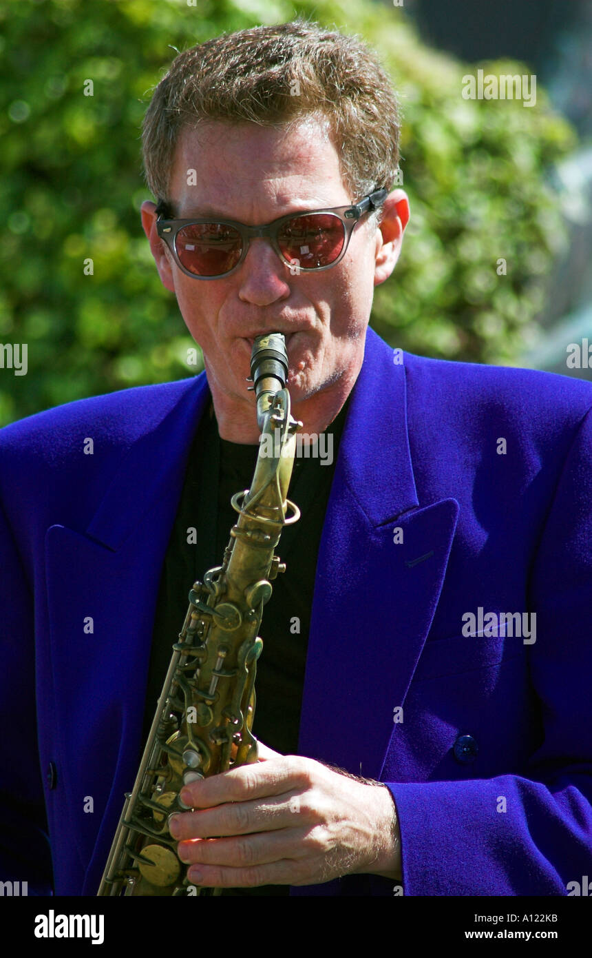 Man wearing a blue jacket playing a saxophone in a band playing at pier ...