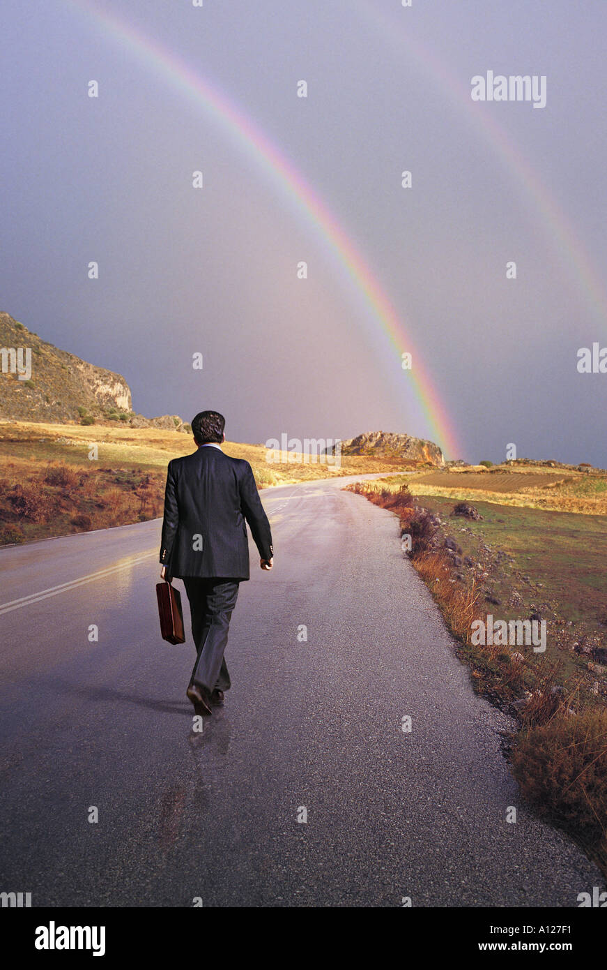 Business man following rainbow Stock Photo - Alamy