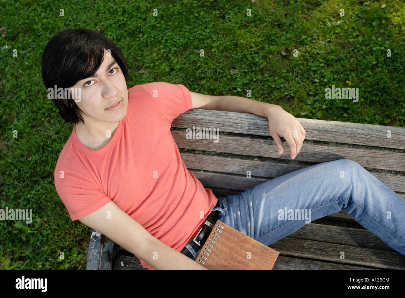 Portrait young Latino male sitting bench from above Stock Photo - Alamy
