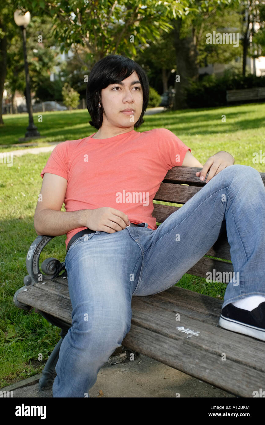 Young man sitting on park bench Stock Photo - Alamy