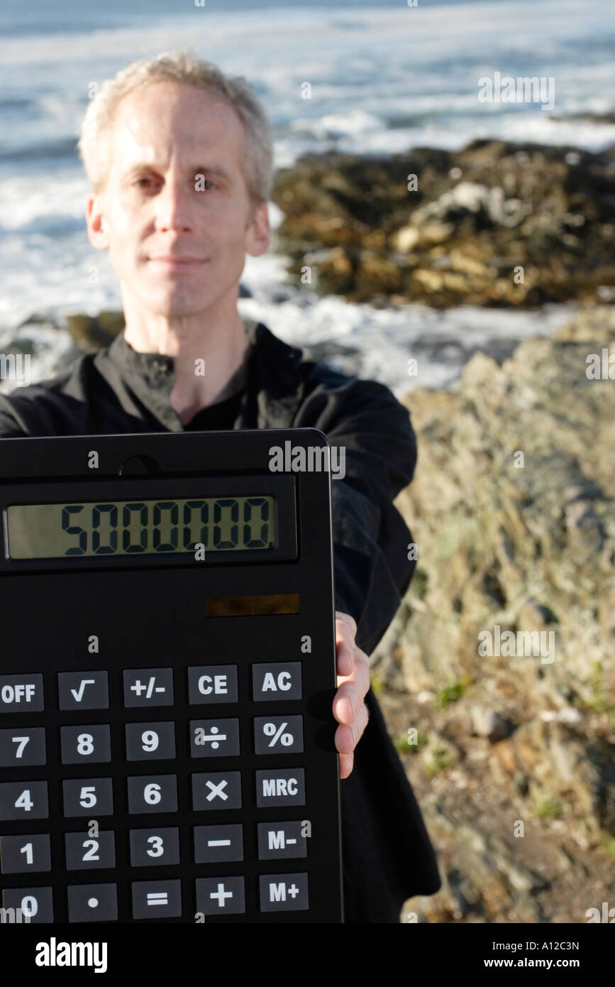 Man holding calculator standing by ocean Stock Photo - Alamy