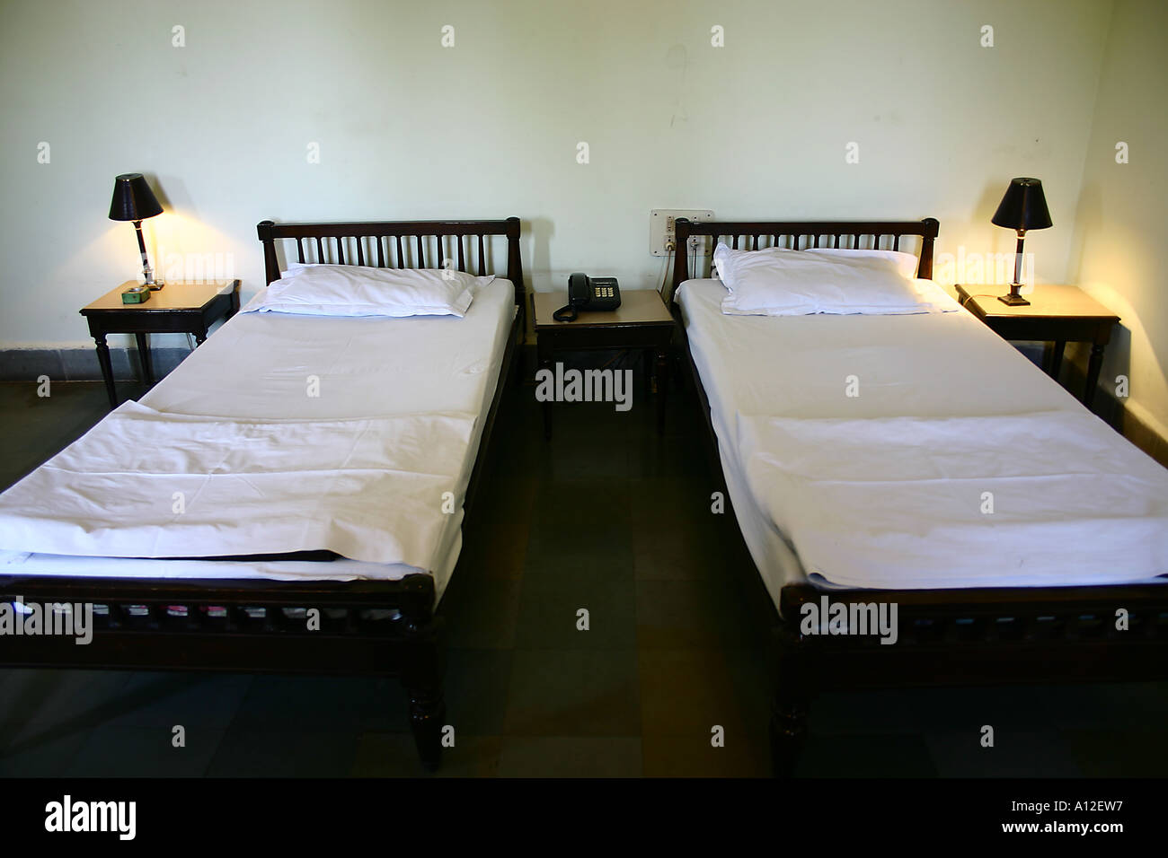Empty double two beds with white sheets pillows side tables lit side ...