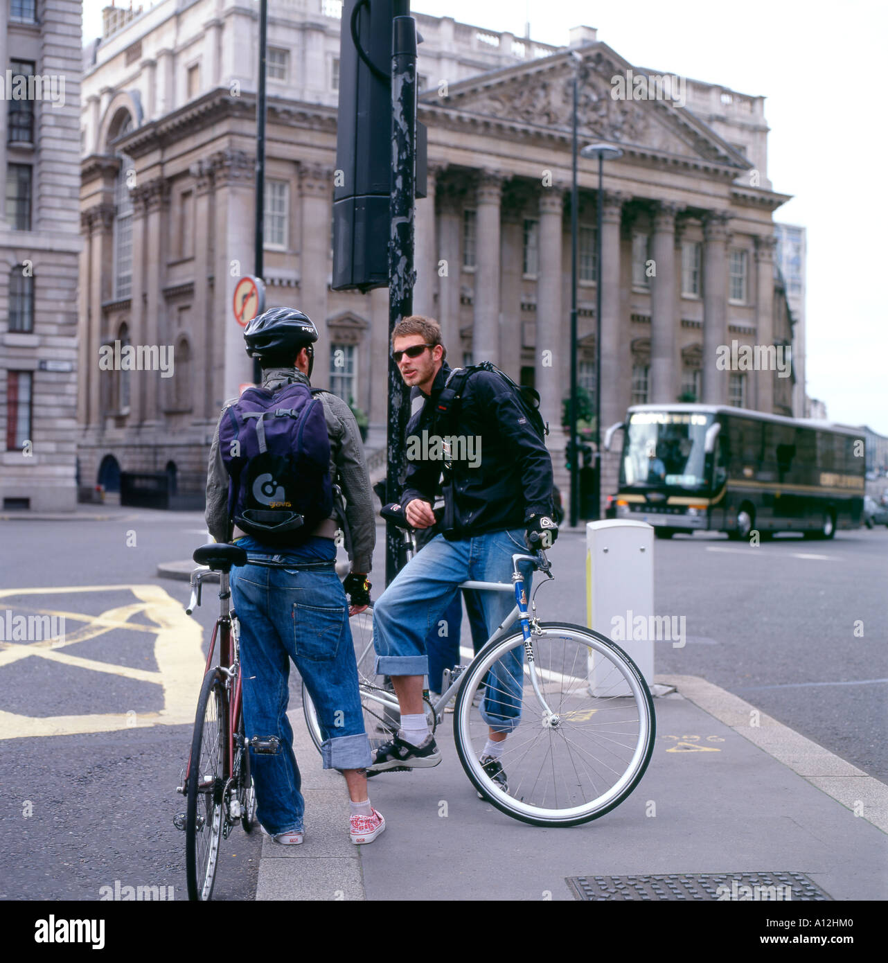 Two male cyclists on bikes stop to talk in conversation at traffic ...