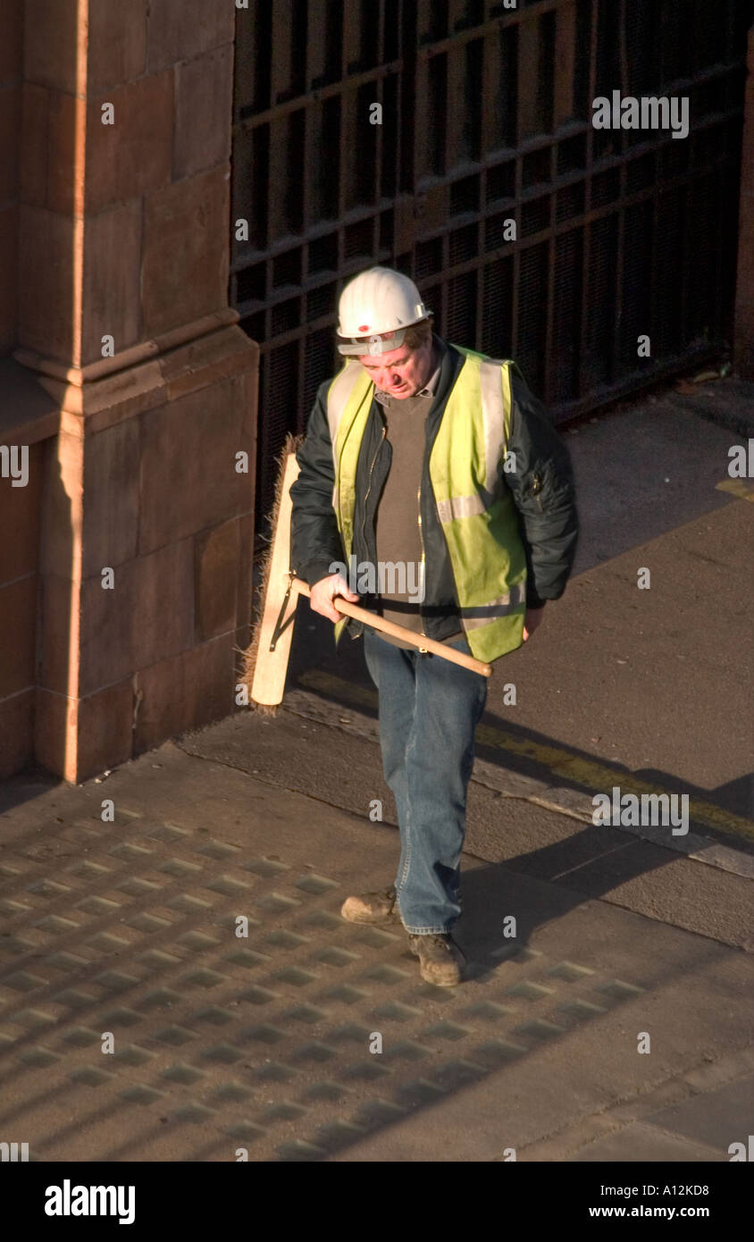 Workman in fluorescent jacket and hardhat holding brush. Tavistock ...