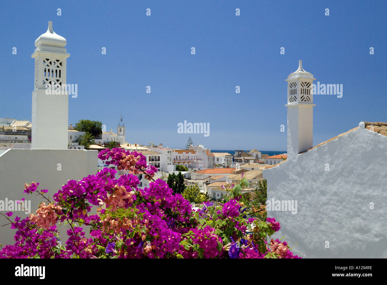 Typical Algarve chimneys, with bougainvillaea flowers and Albufeira and ...
