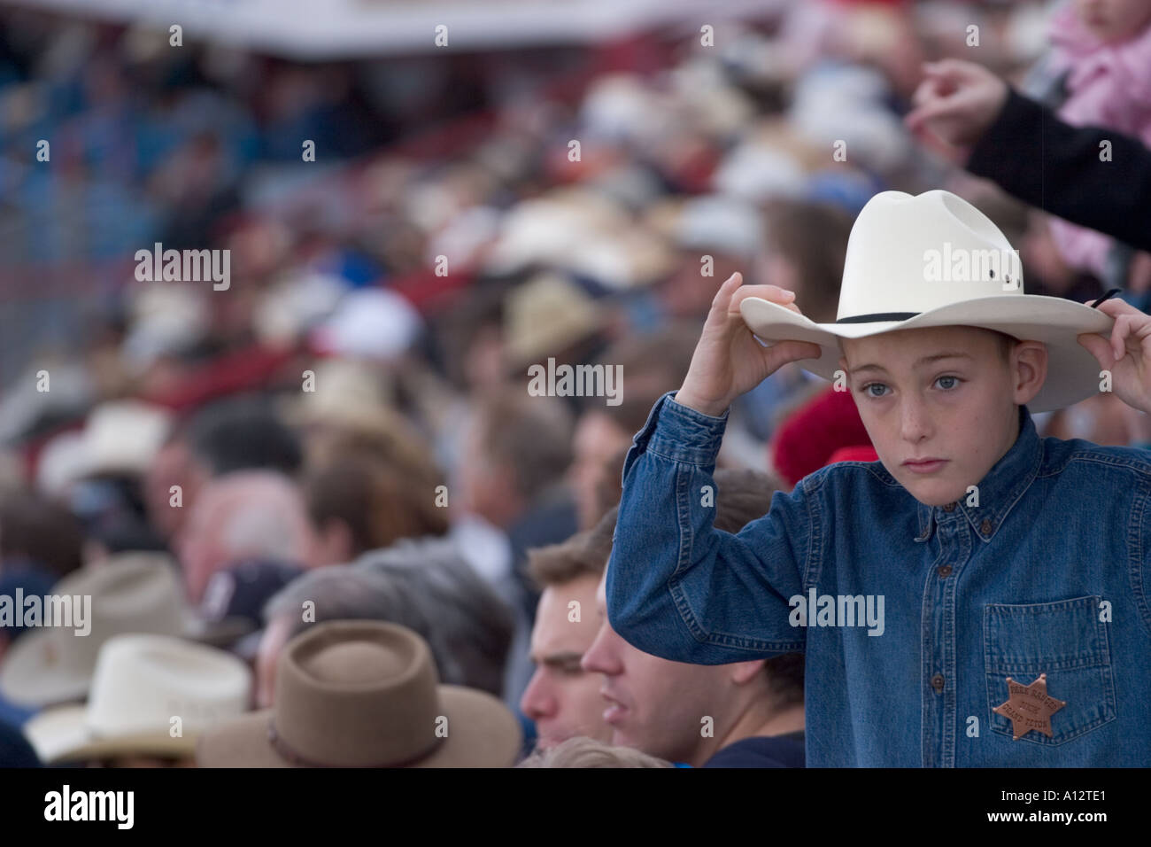 At the Tucson Rodeo a kid adjusts his hat while watching the ...