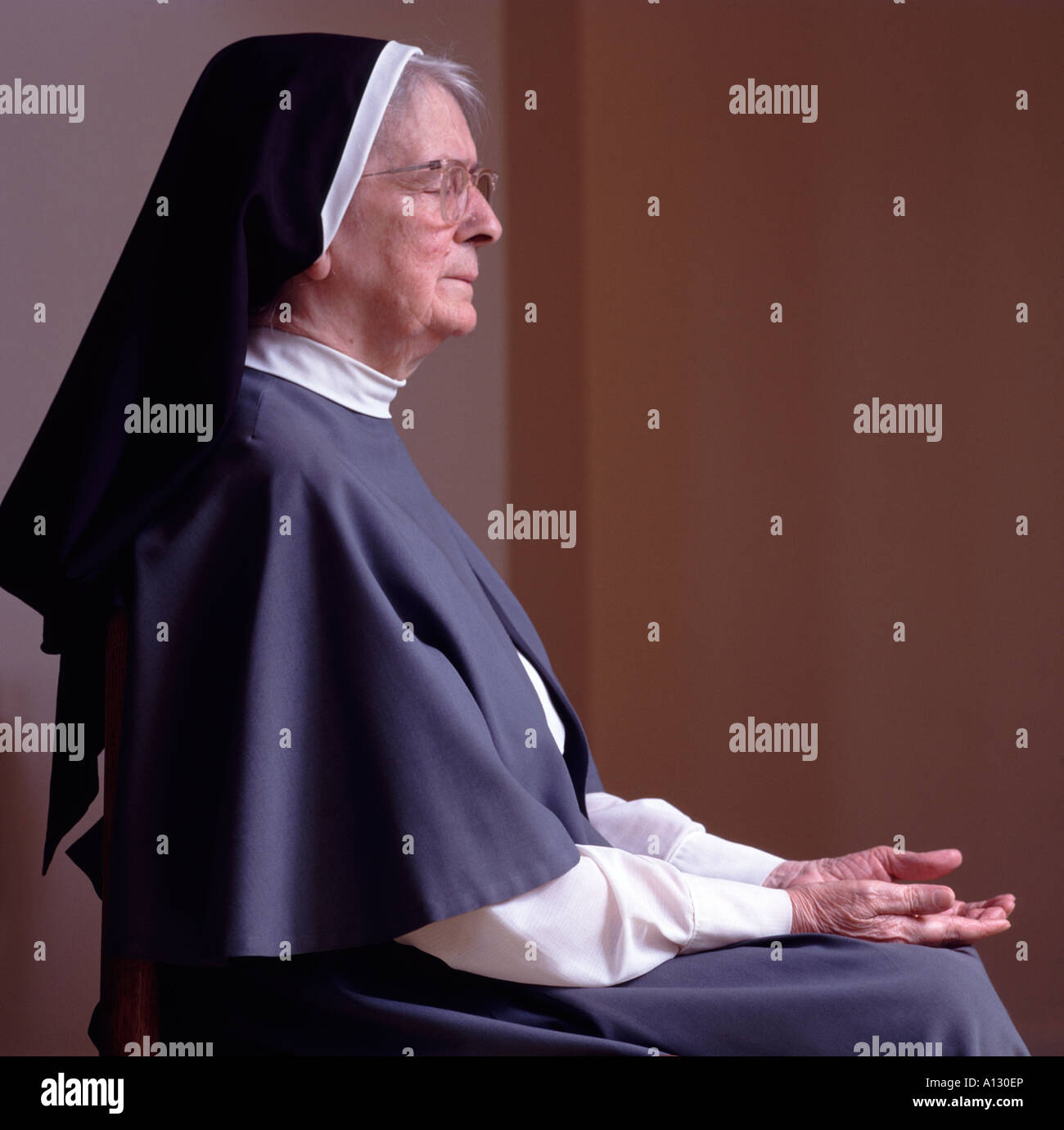 Nun sitting on chair praying Stock Photo - Alamy