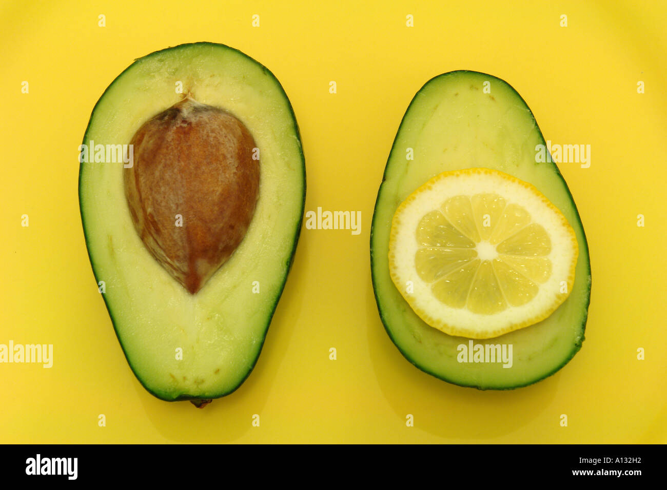 Two avocado halves on a yellow background Stock Photo - Alamy