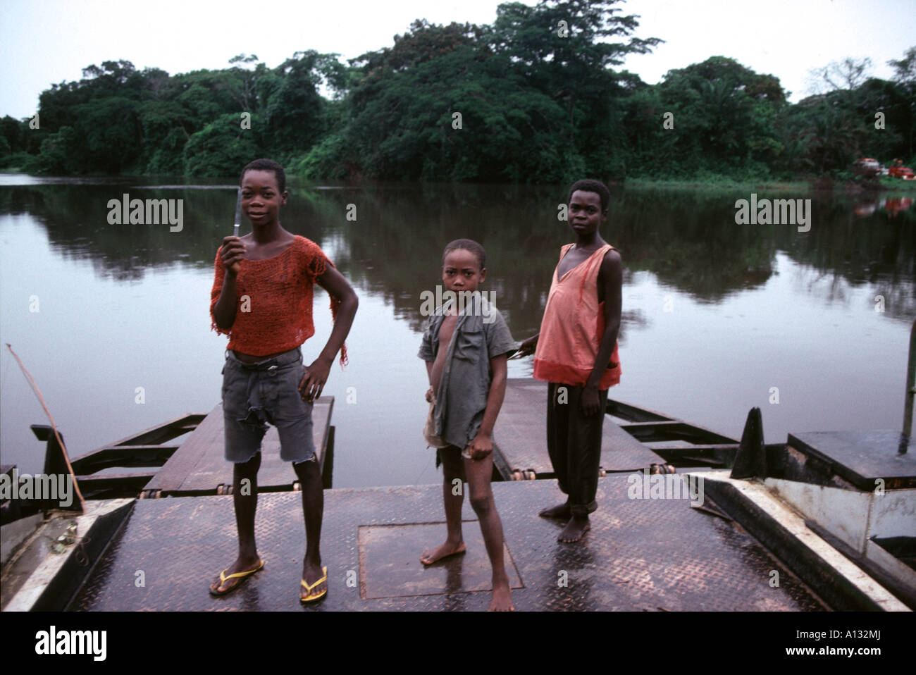 Three locals pose on a ferry on the Oubangui River in the Democratic ...
