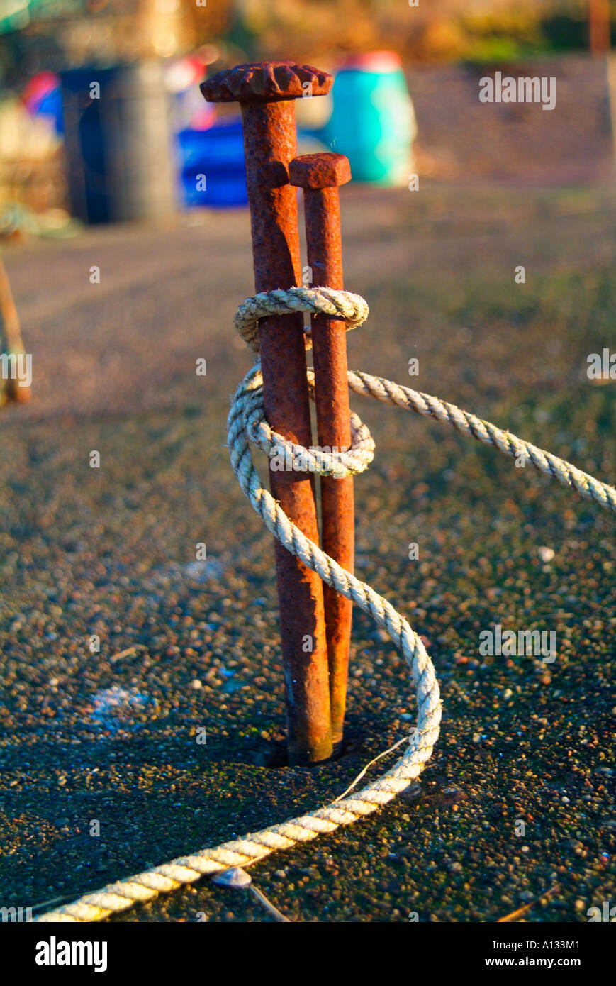 two metal rusted pegs with rope tied around for safety Stock Photo - Alamy