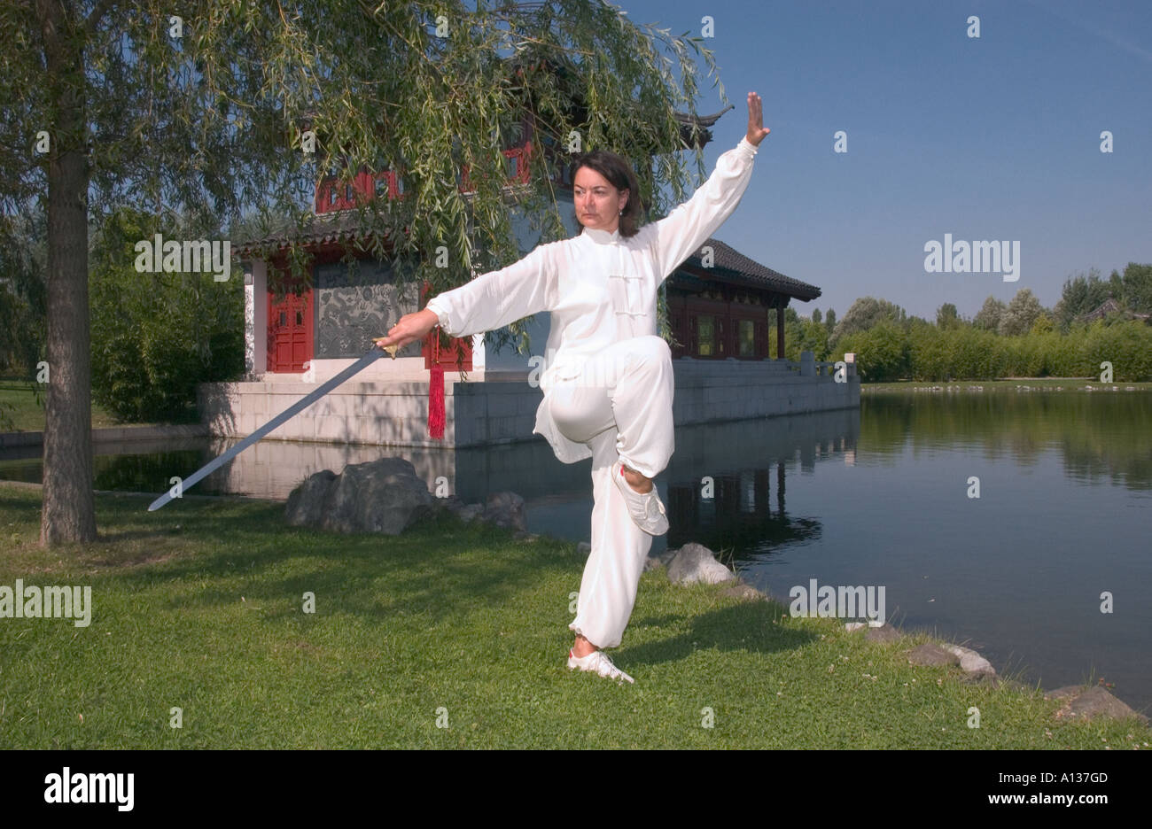 woman exercising tai chi with a sword in front of a chinese temple ...