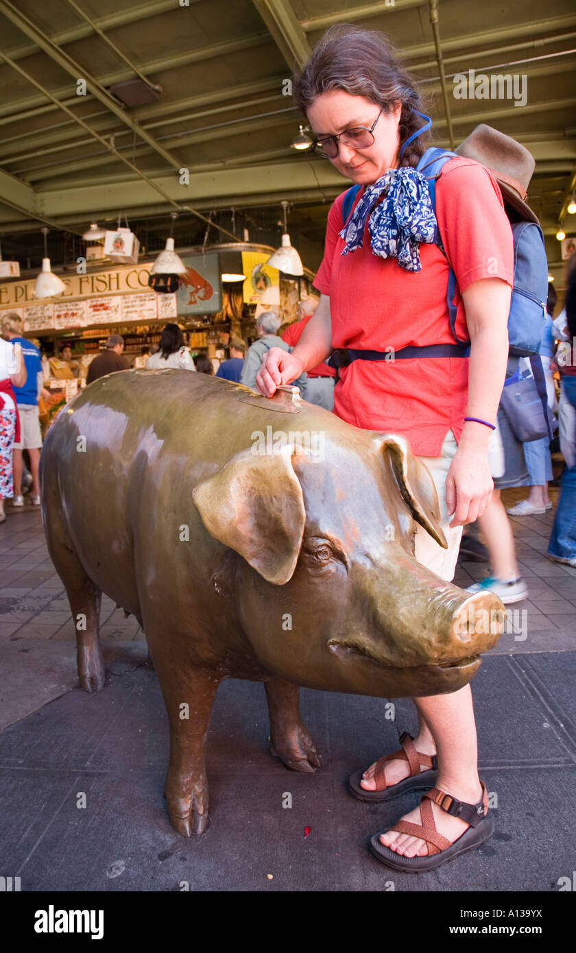 Woman putting money for charity into the brass pig "Pike Place" market ...