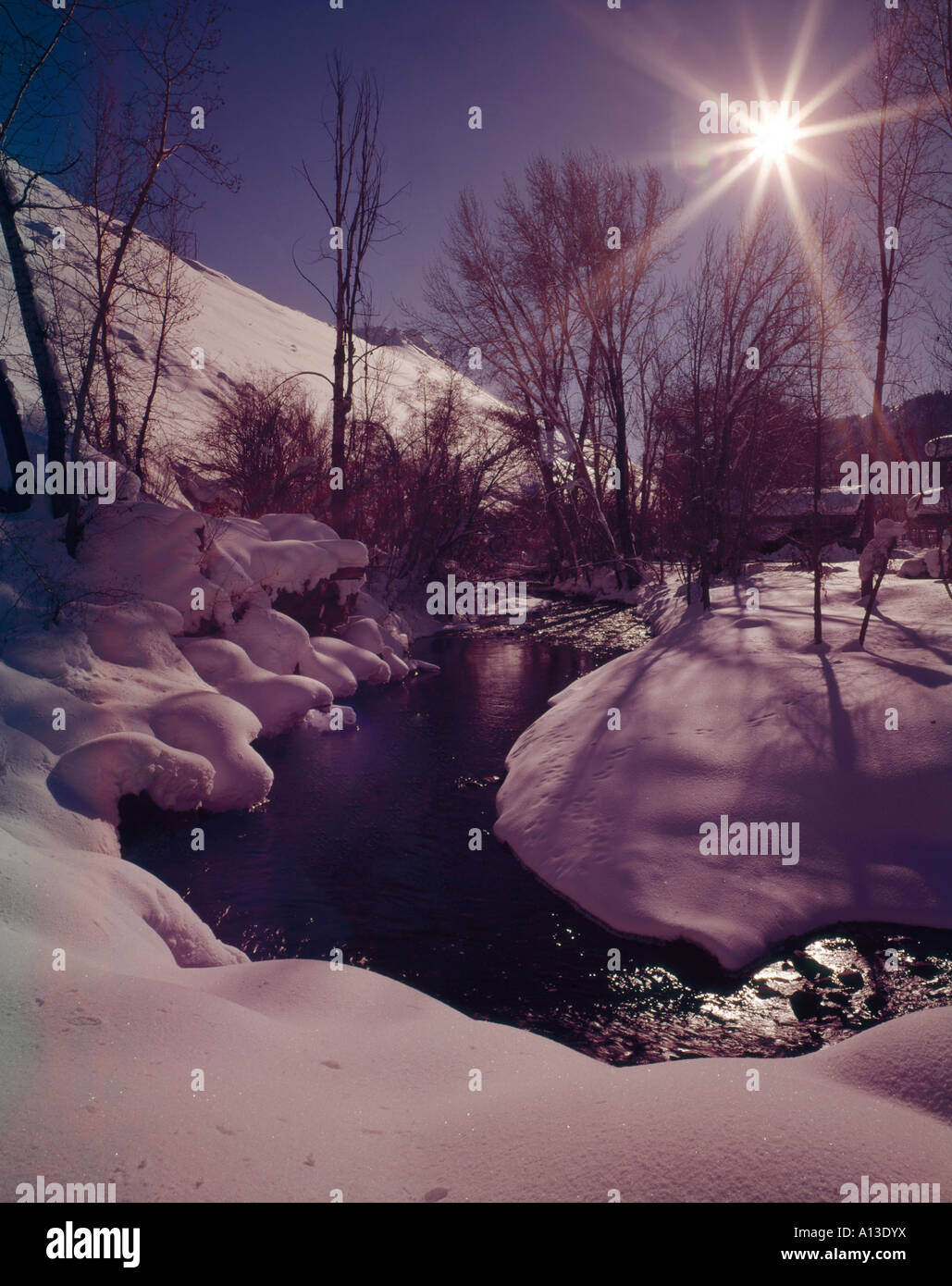 Sunburst fills sky in winter photo of snowy stream Stock Photo - Alamy