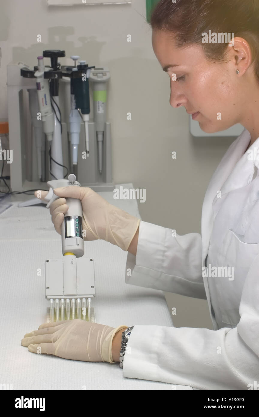 A female scientist pipetting a reagent into a microplate during a ...