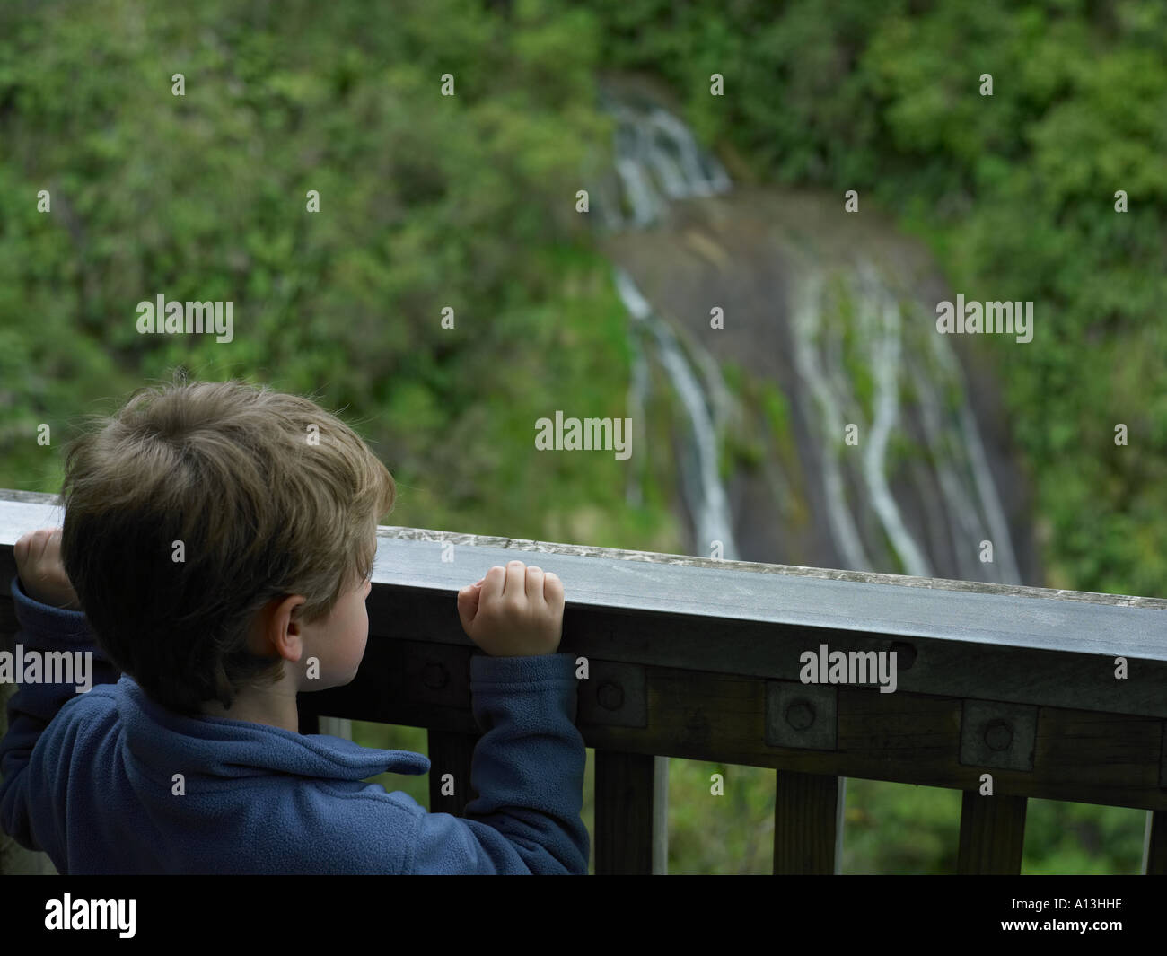boy looking over the safety rail at an outlook of a waterfall Stock ...