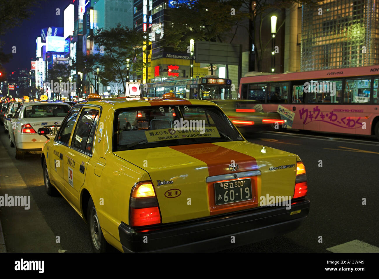 A colourful yellow taxi parked on a busy Tokyo street at night Stock ...