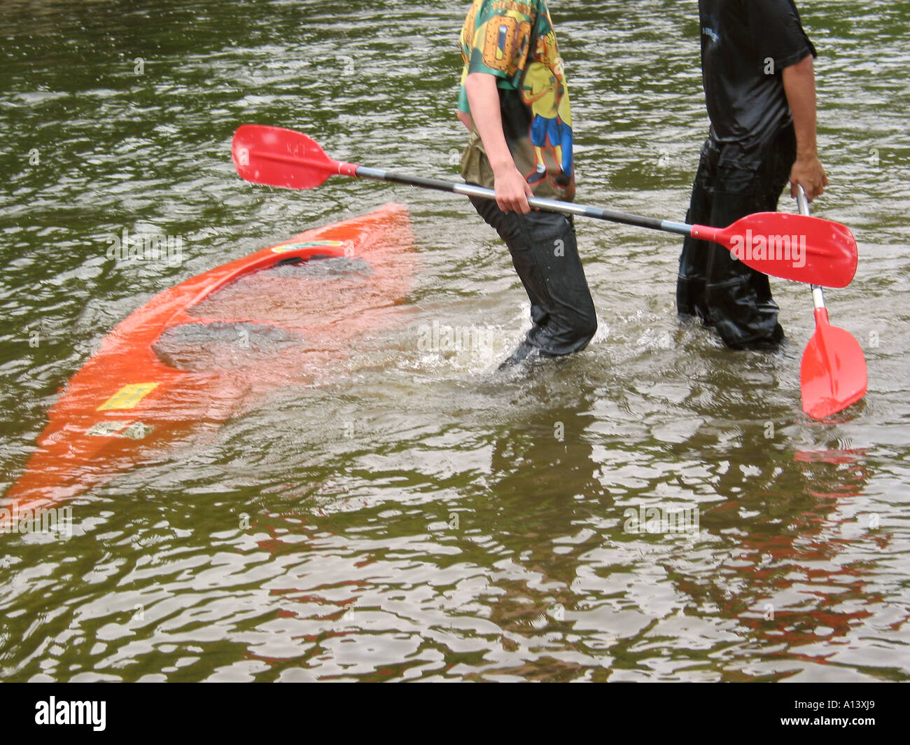 Sunken canoe with two people standing in knee deep water Stock Photo ...