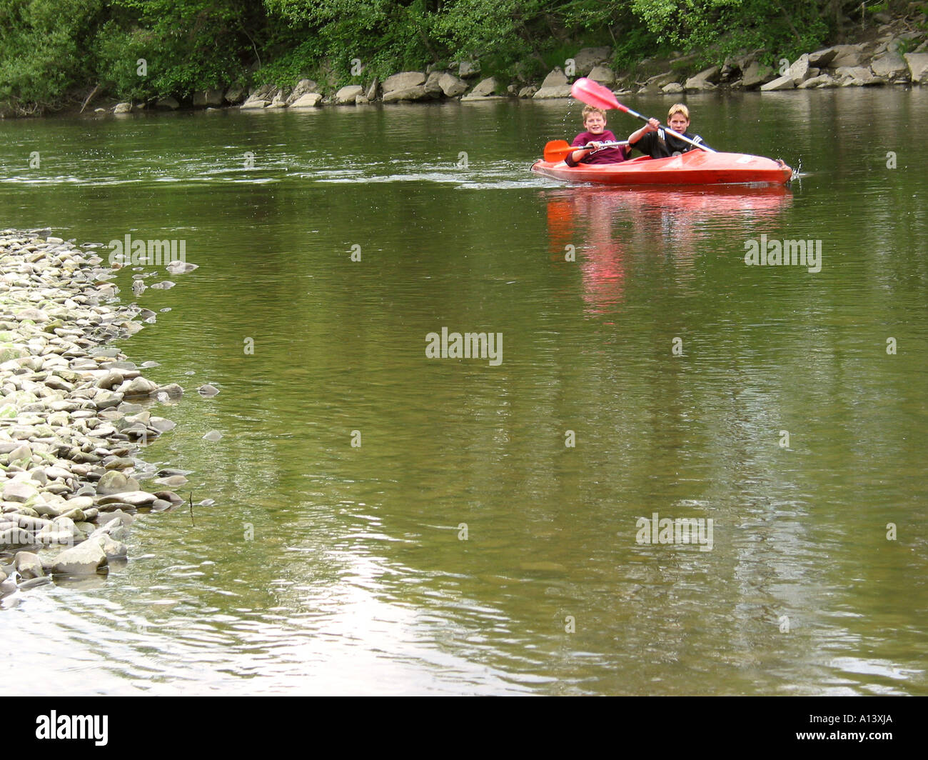 two teenagers on an idyllic canoe trip on calm river in Belgian ...