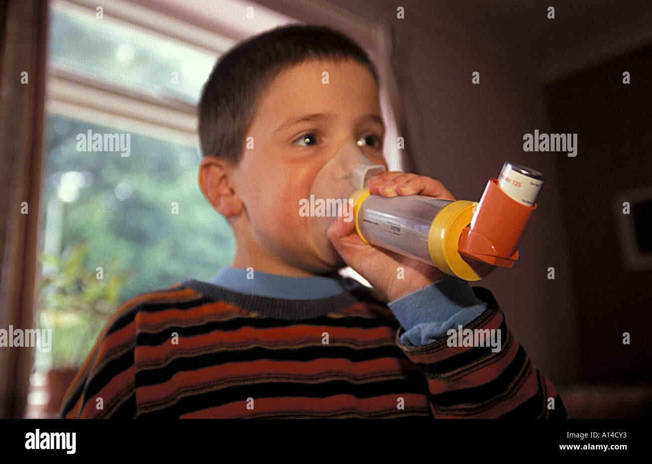 Child using ashma inhaler indoors Stock Photo - Alamy