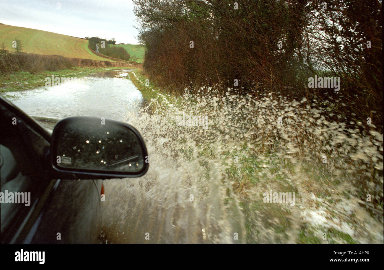 Driving along flooded road in the Windrush Valley in Oxfordshire ...