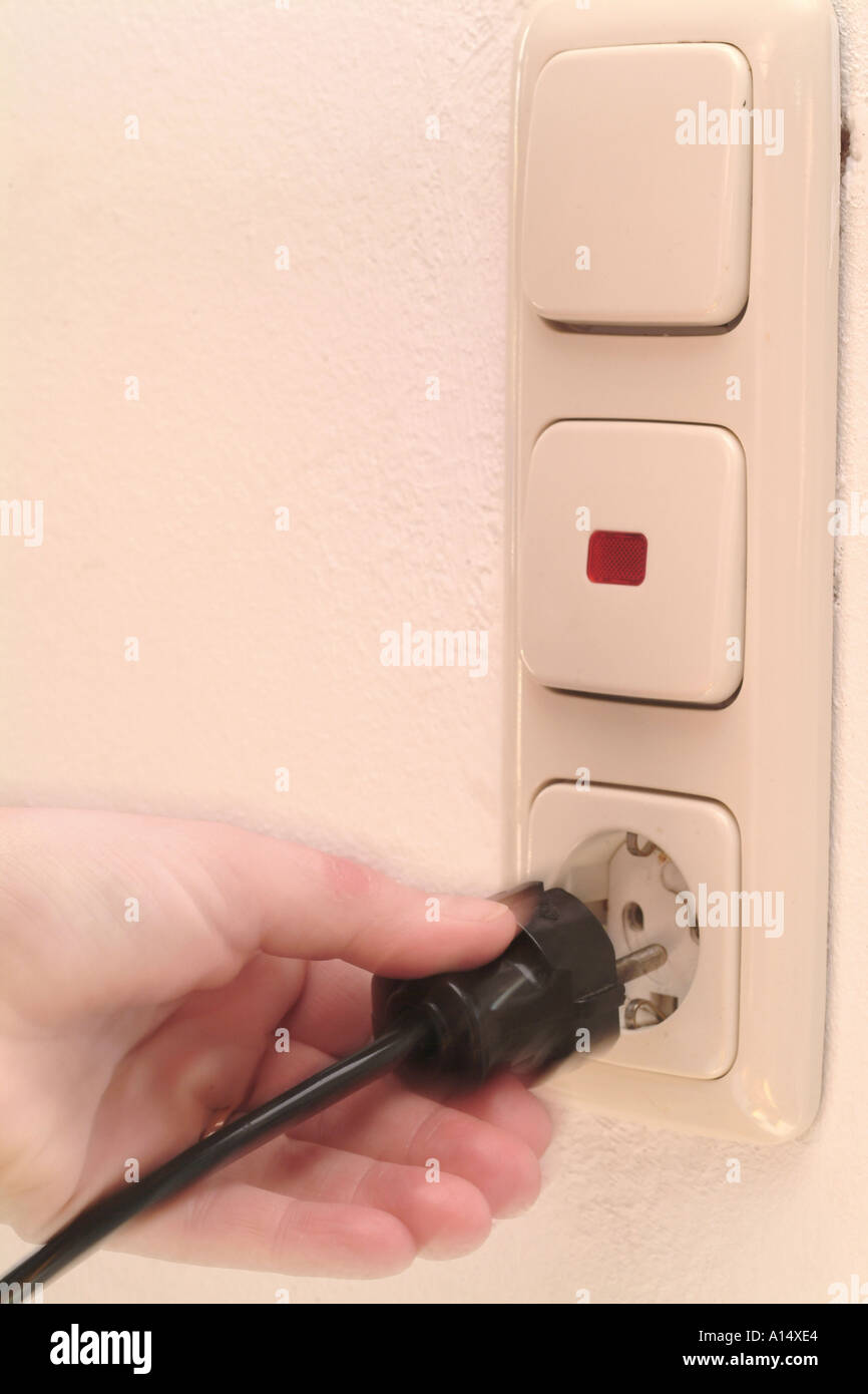 hand pulls plugs from plug socket Stock Photo - Alamy
