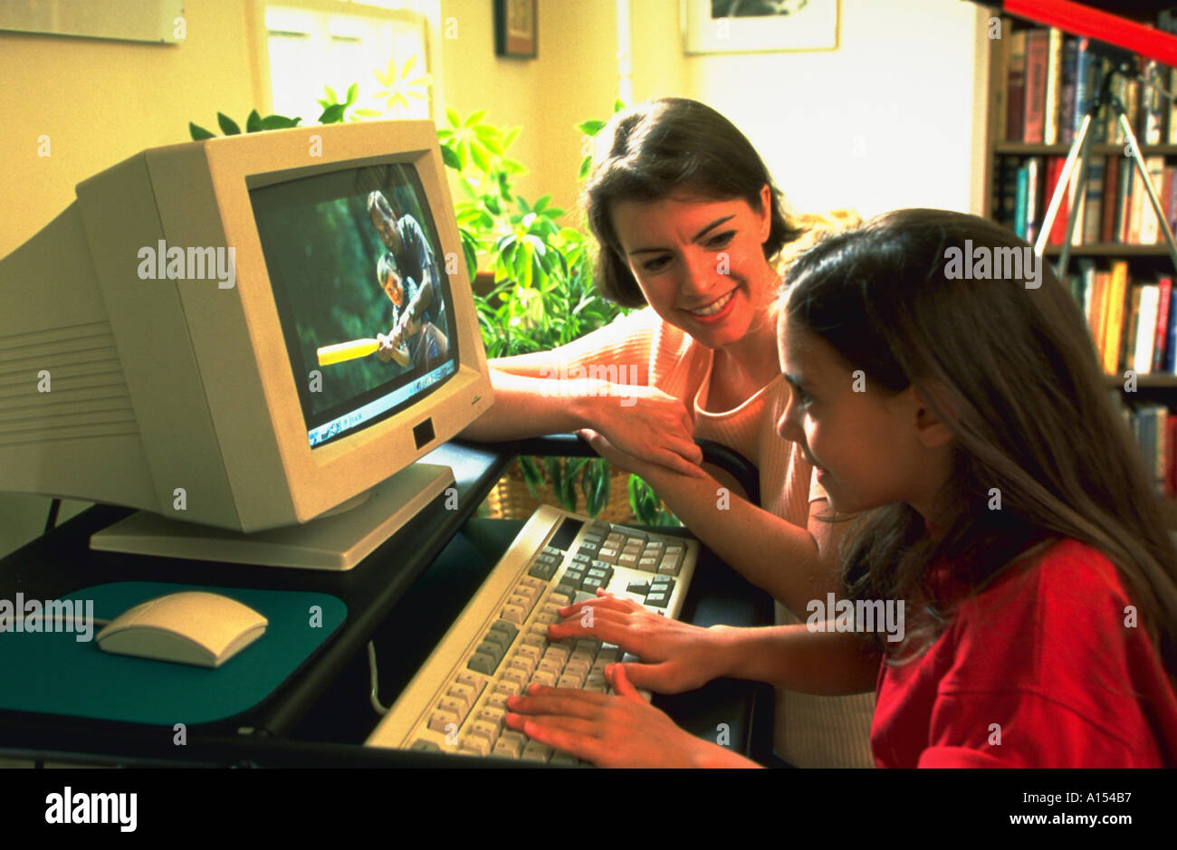 A mother looks on as her daughter uses a computer Stock Photo - Alamy