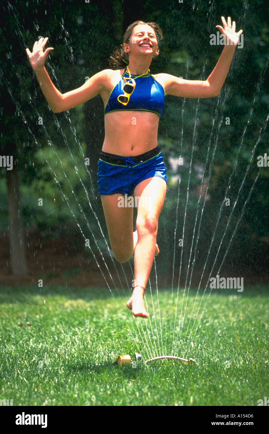 A young woman running through a sprinkler in the grass Stock Photo - Alamy