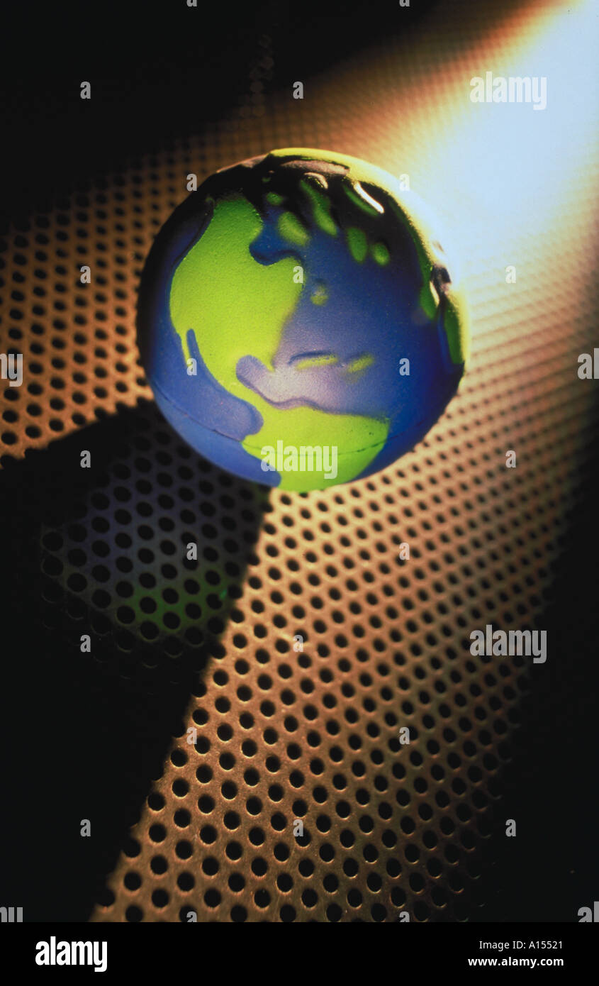 Still life of a globe sitting on a holed surface casting a long shadow ...