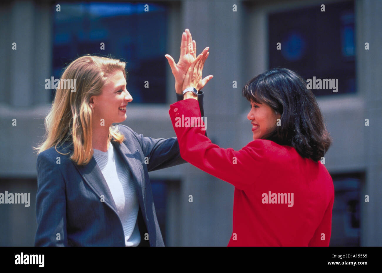 Two female business executives high five each other in celebration ...