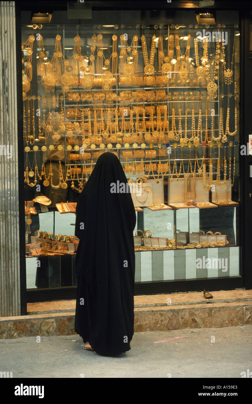 Woman in traditional dress looking into gold shop window Bahrein Middle ...