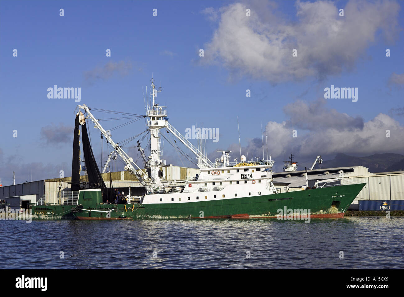 Tuna trawler alongside processing plant loading nets prior to putting ...