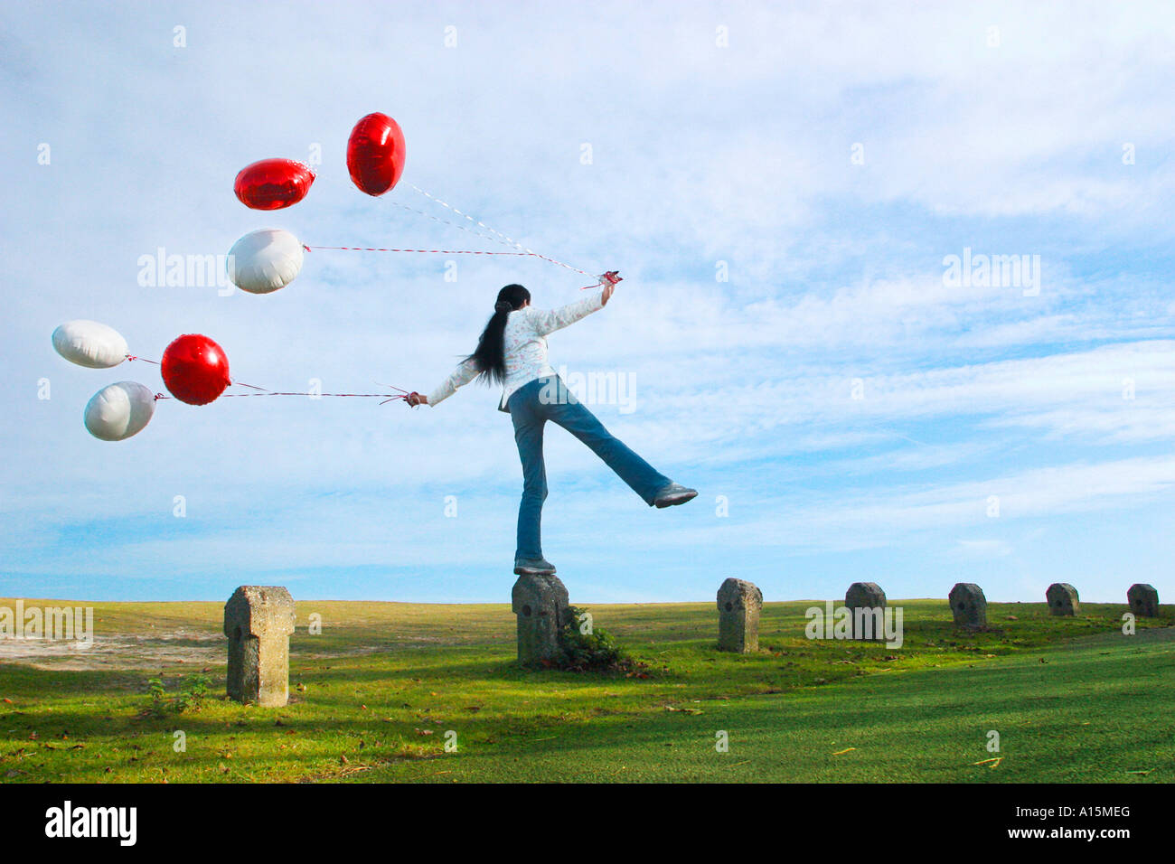 Woman balancing on concrete bollards holding balloons Stock Photo - Alamy