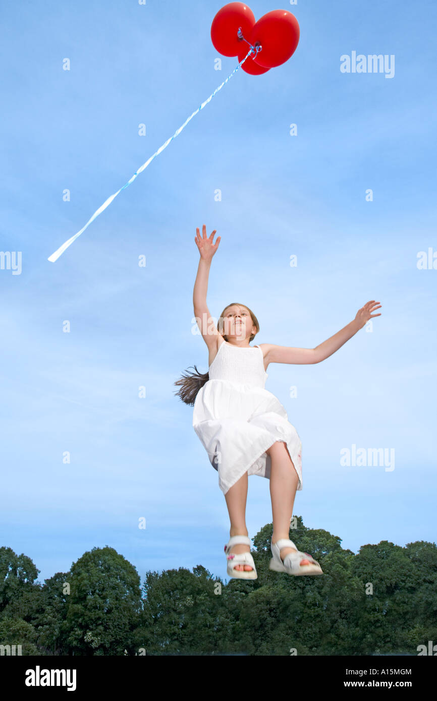 Girl jumping in air reaching for red balloons Stock Photo - Alamy