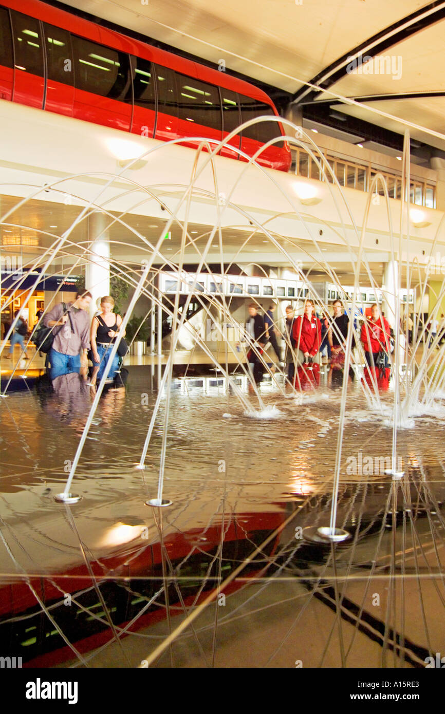 Passengers watch dancing fountain spurt water with red tram overhead in ...
