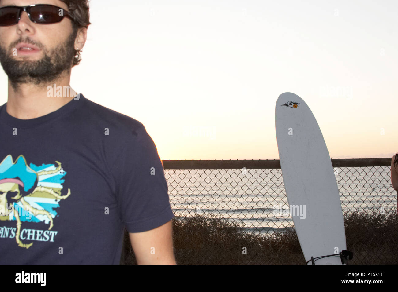 A horizontal image of a bearded man at the beach at sunset with a surf ...