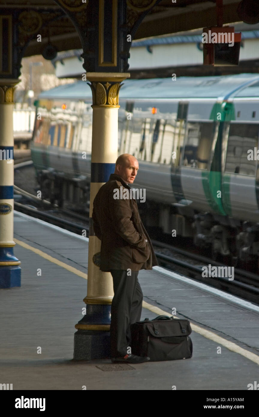 Vertical view of a solitary man leaning on a pillar on the platform ...