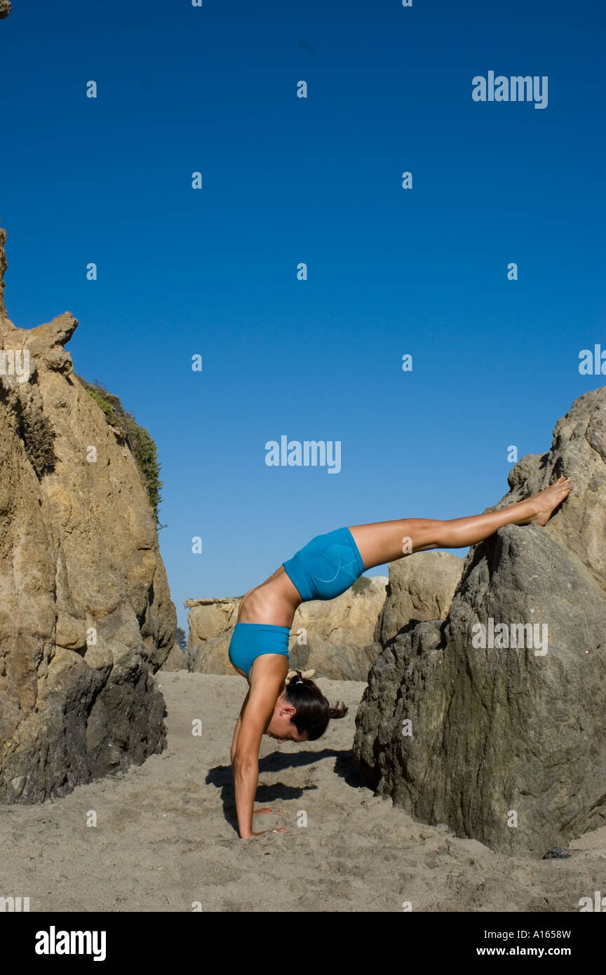 Young woman practicing yoga on beach between rocks Stock Photo - Alamy