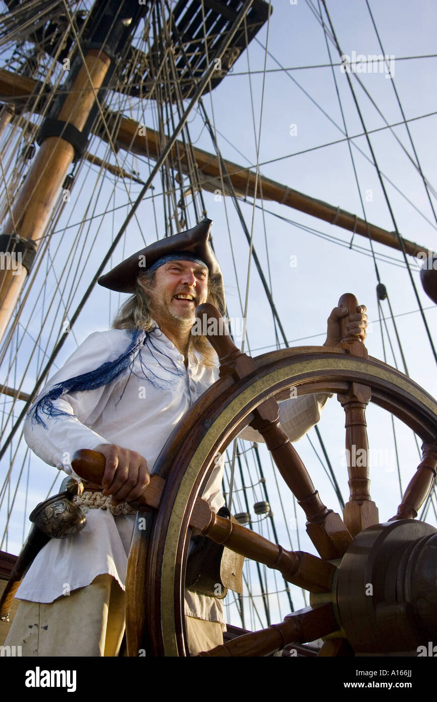 Laughing pirate at the wheel of the 18th century mano' war Grand Turk ...