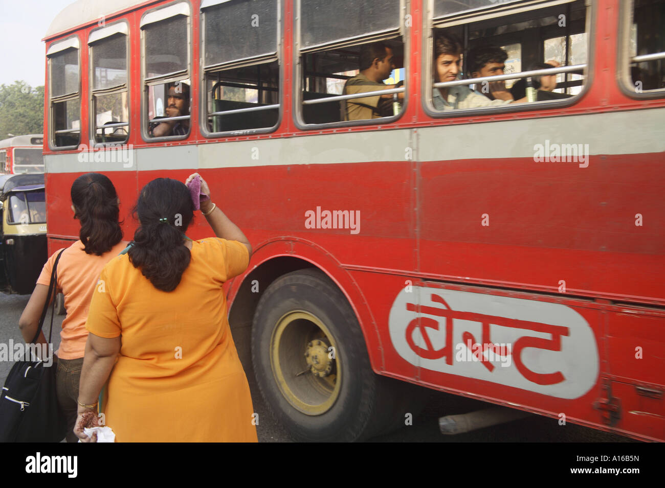 RSC102017 Two ladies crossing the street while red bus passes Mumbai ...