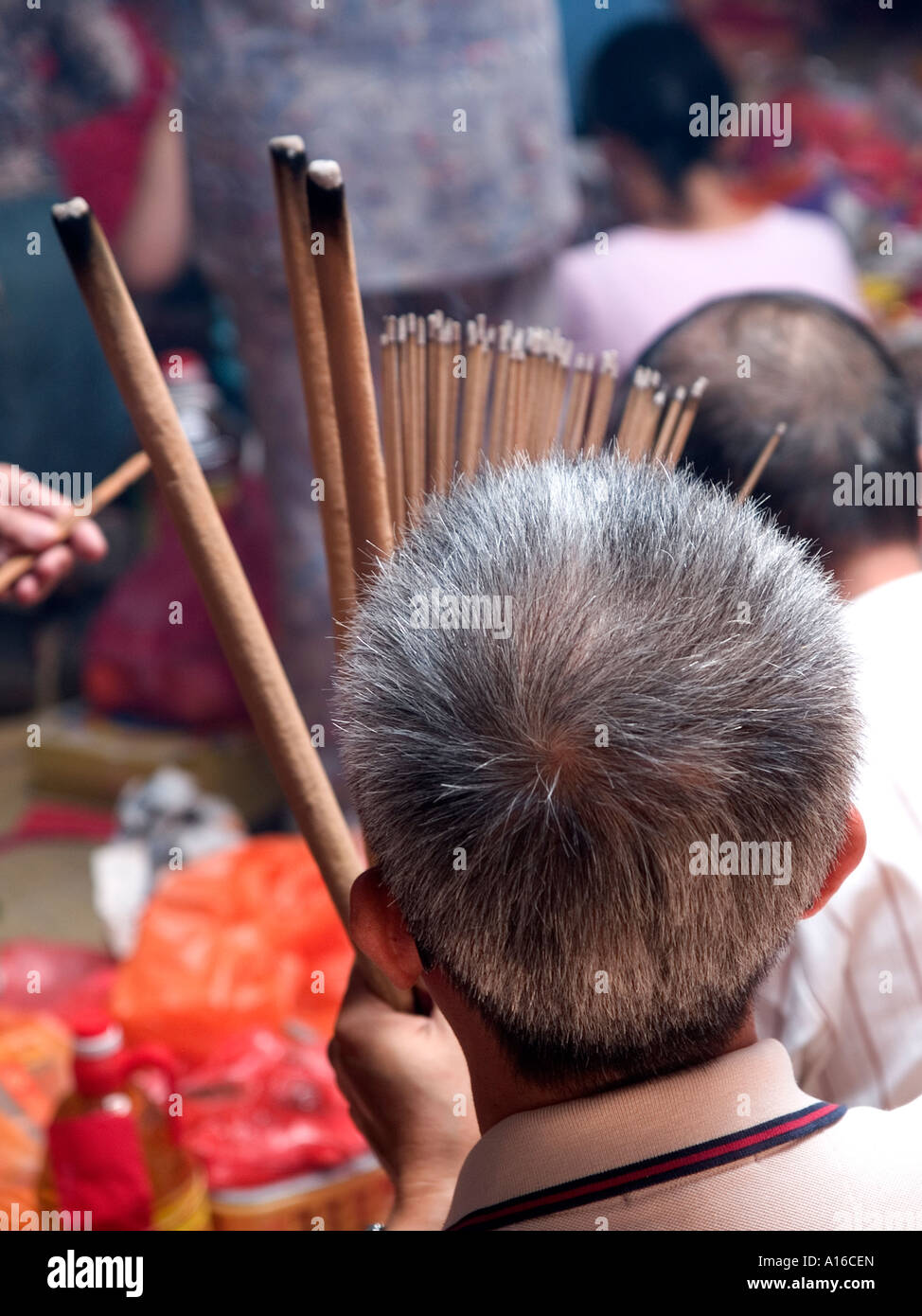 Taoist devotee praying with lighted joss sticks to the Emperor God ...