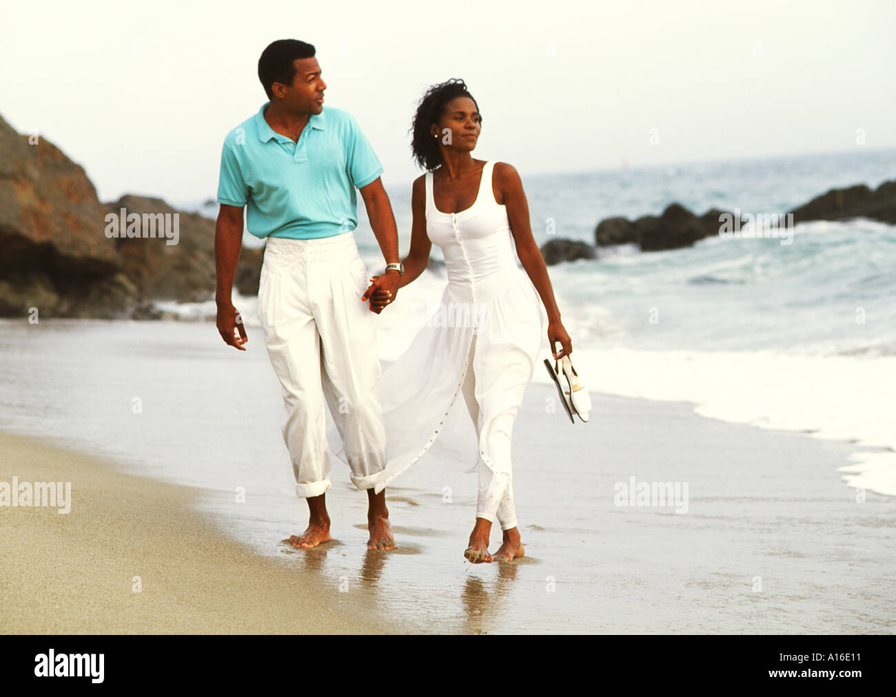 Black couple walking together on the beach with waves on shore Stock ...