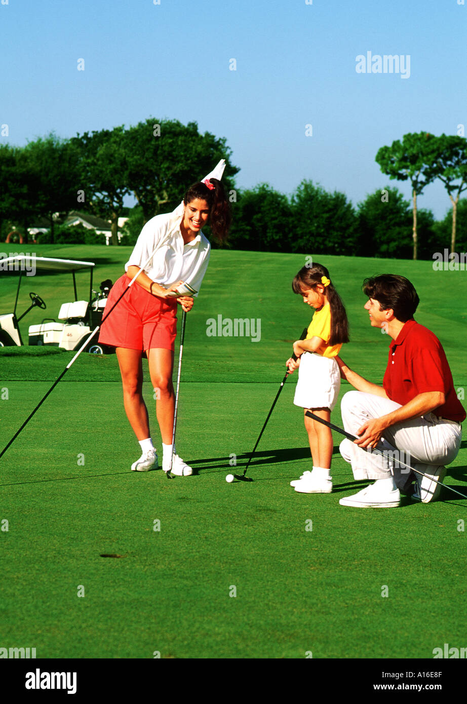 Hispanic family having fun playing golf together putting Stock Photo ...