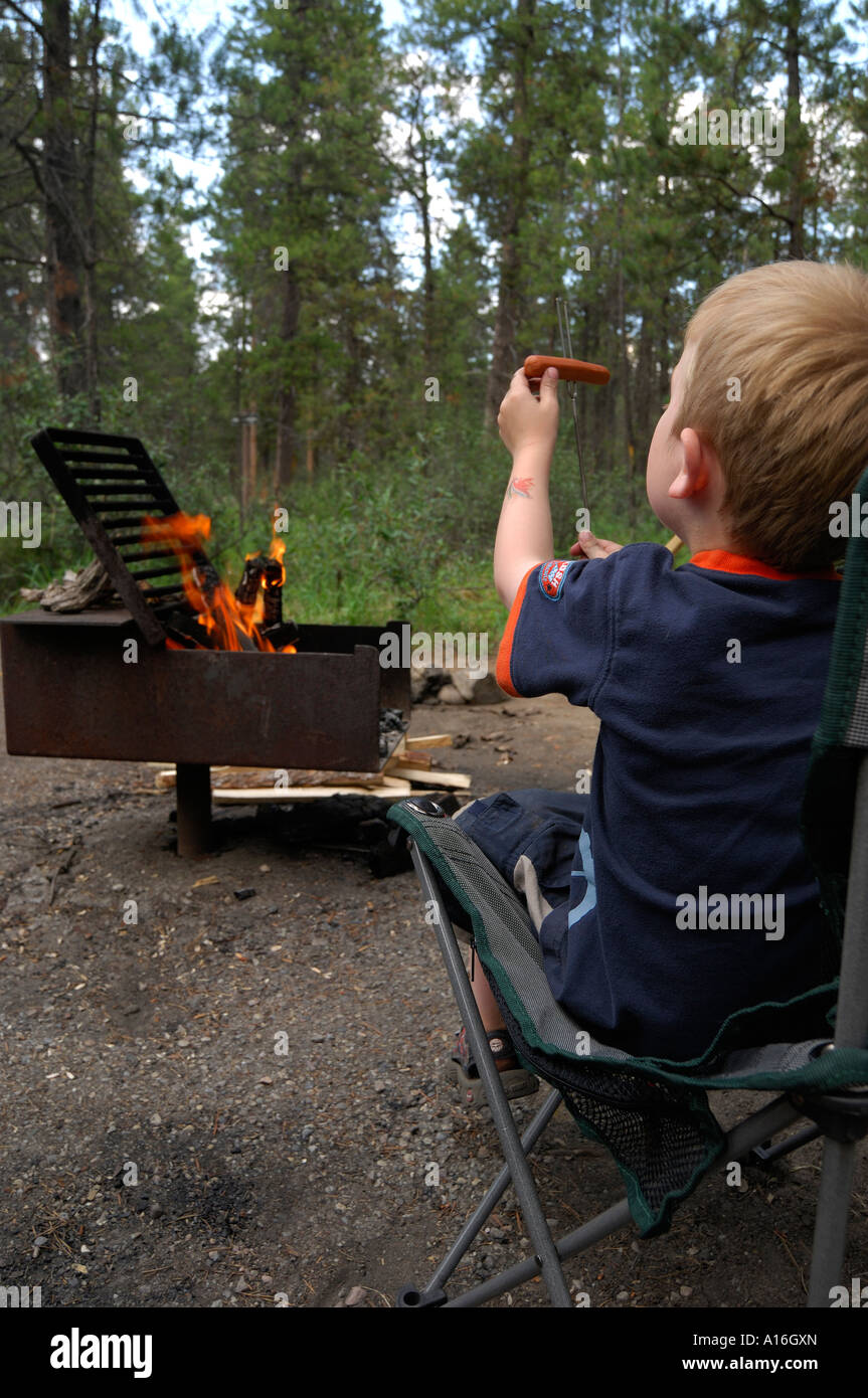Young boy cooking a hotdog over a campfire Stock Photo - Alamy