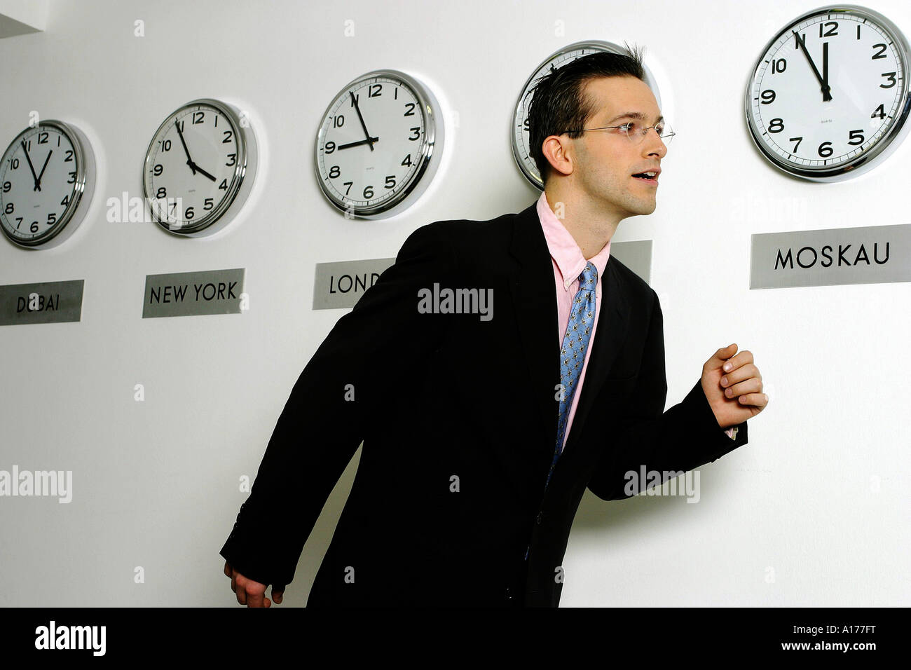 Man under stress in front of world time clocks Stock Photo - Alamy