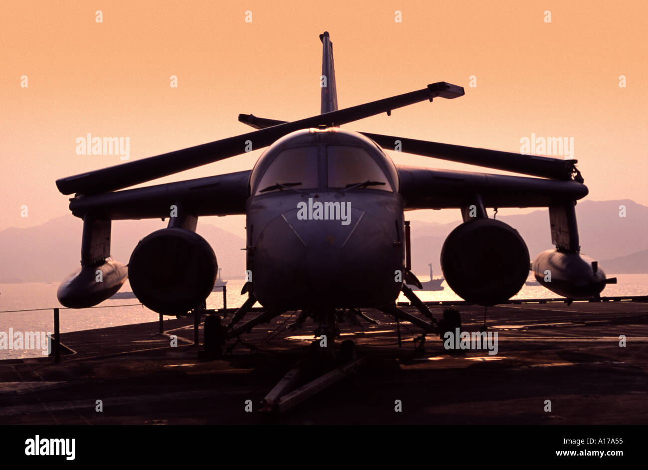 War plane with wings folded at the USS Constellation flagship at sunset ...