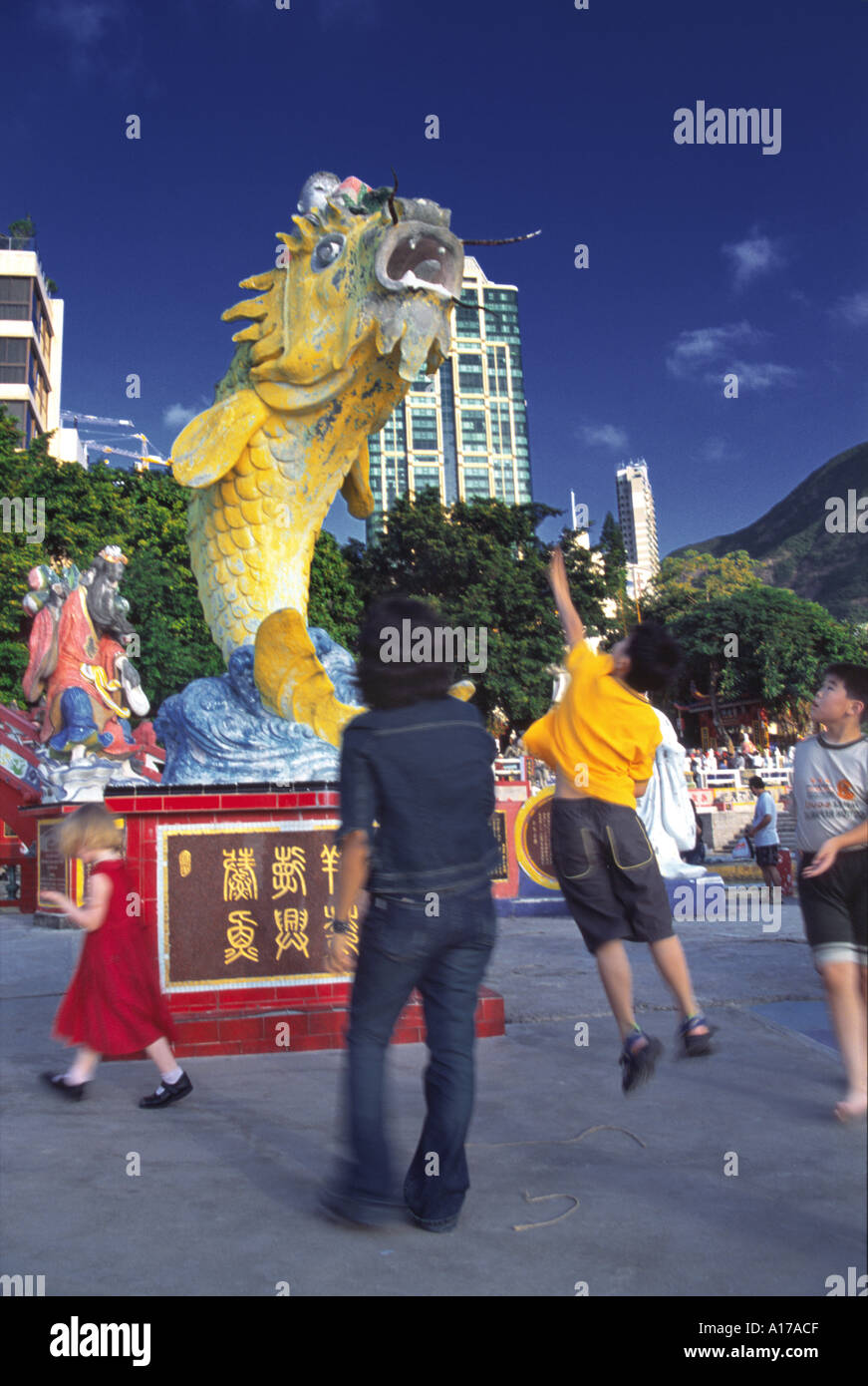 Kids try their good fortune by throwing a coin inside the mouth of a ...