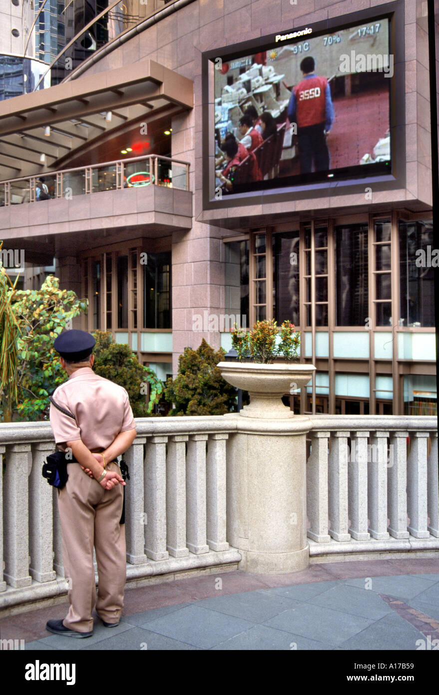 Security guard watching stocks development on an open air giant TV in ...