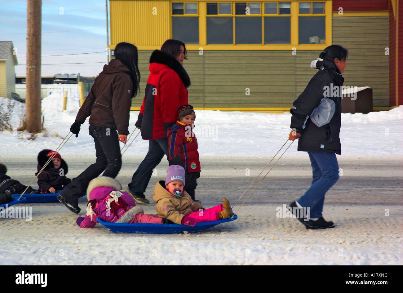 Inuit women pulling their children in sledges in the arctic village of ...