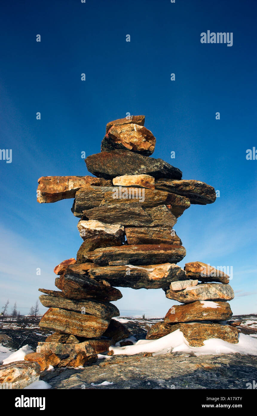 High clouds behind an inukshuk on a hill overlooking the arctic village ...