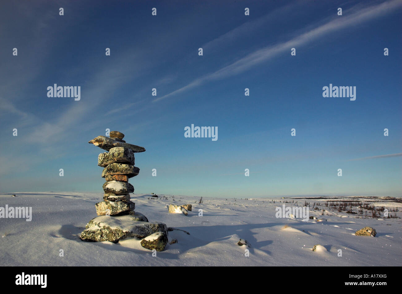 High cloud behind an inukshuk surrounded by deep snow in the Canadian ...